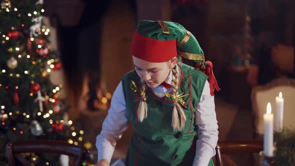 Curious elf with envelopes on the background of Christmas tree and a ...