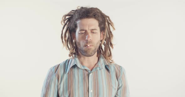 Man with dreadlocks smoking medicinal marijuana on white background ...