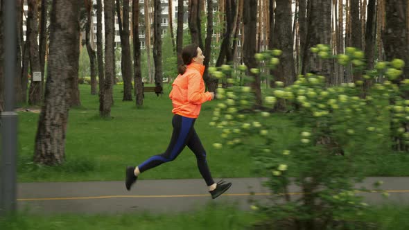 Young fit skinny woman running in city park on rainy day. Marathon ...