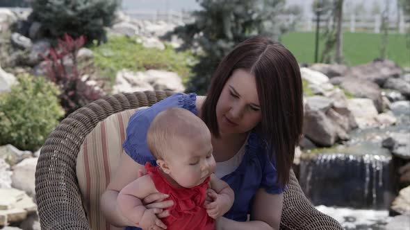 Woman holding child in lap while rocking in a rocking chair, by JBFProd