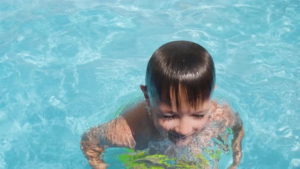 Caucasian boy emerges from pool water, happy kid looking into camera ...