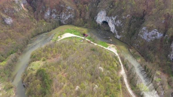 Aerial Above View of a Wild Mountain River Meander and a Gigantic Cave ...