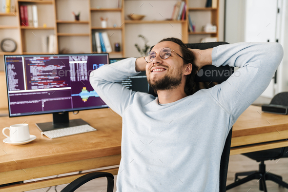 Image of joyful programmer man smiling and resting while working Stock ...