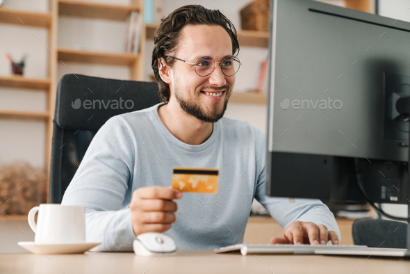 Image of programmer man holding credit card while working with computer ...