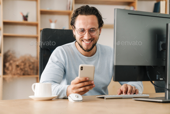 Image of programmer man using cellphone while working with computer ...