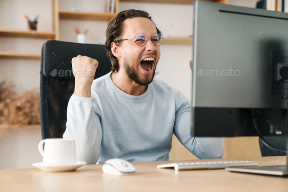 Image of programmer man making winner gesture working with computer ...