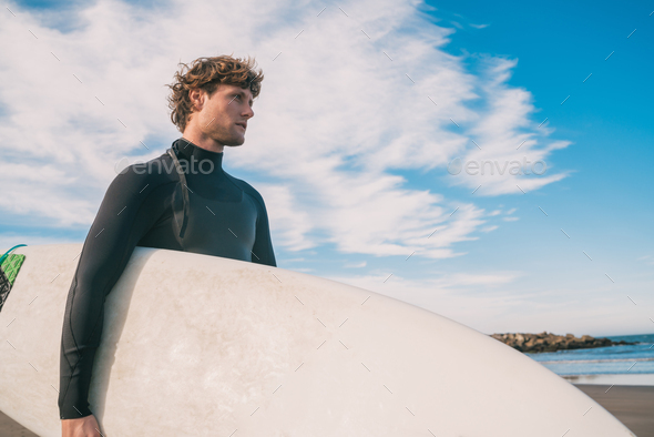 Surfer standing in the ocean with his surfboard. Stock Photo by megostudio
