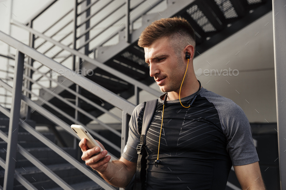 Image of young athletic sportsman using cellphone while working out ...