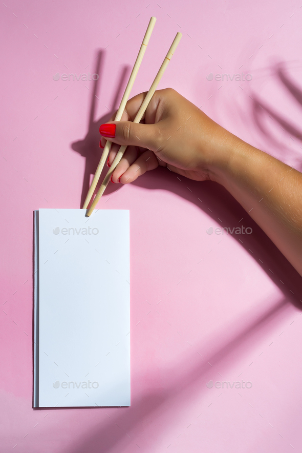 Woman's hand holds brochure by wooden sticks Stock Photo by lyulkamazur