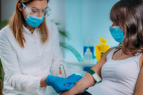 Medical worker with PPE taking blood sample from patient in a hospital ...