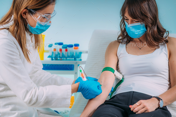 Medical worker with PPE taking blood sample from patient in a hospital ...