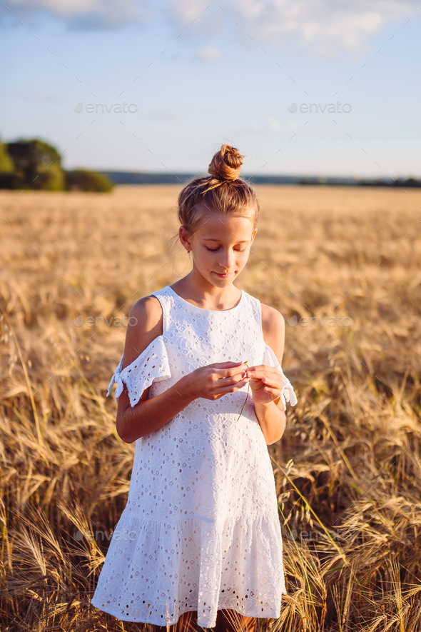 Happy cute girl in wheat field outdoors Stock Photo by travnikovstudio