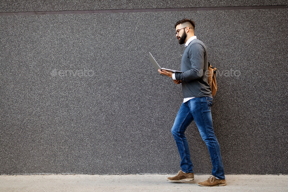 Businessman walking in street holding his laptop, working outdoor Stock ...