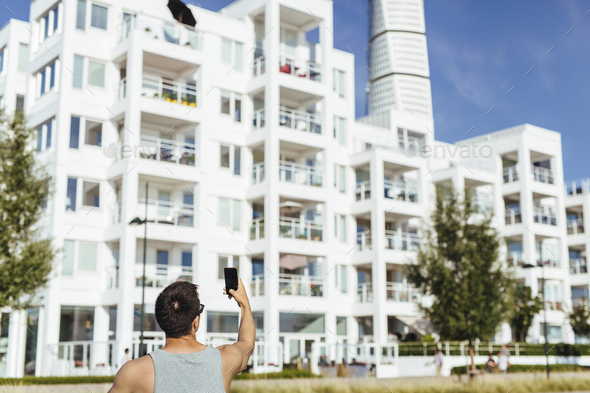 Rear view of man photographing apartment building Stock Photo by ...