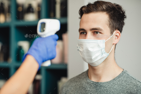 Millennial guy getting body temperature measuring with touchless thermometer Stock Photo by ...