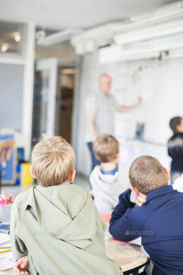 Children looking at teacher during lecture in classroom Stock Photo by ...