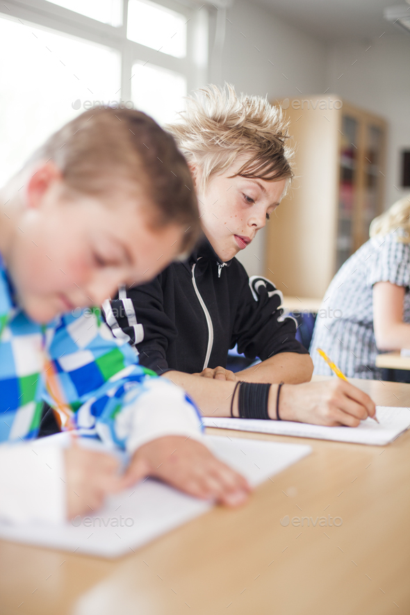 Junior high students writing at desk in classroom Stock Photo by ...