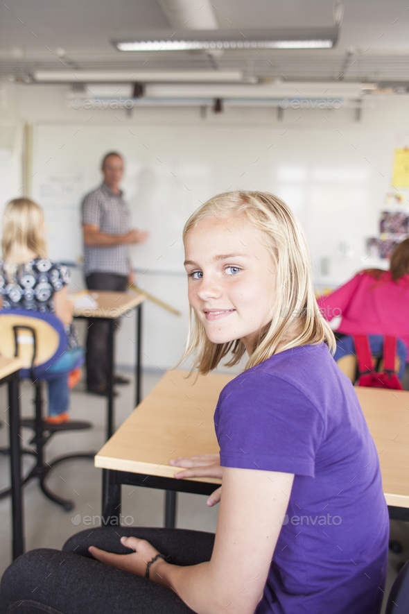 Side view of portrait of smiling girl sitting in classroom Stock Photo ...