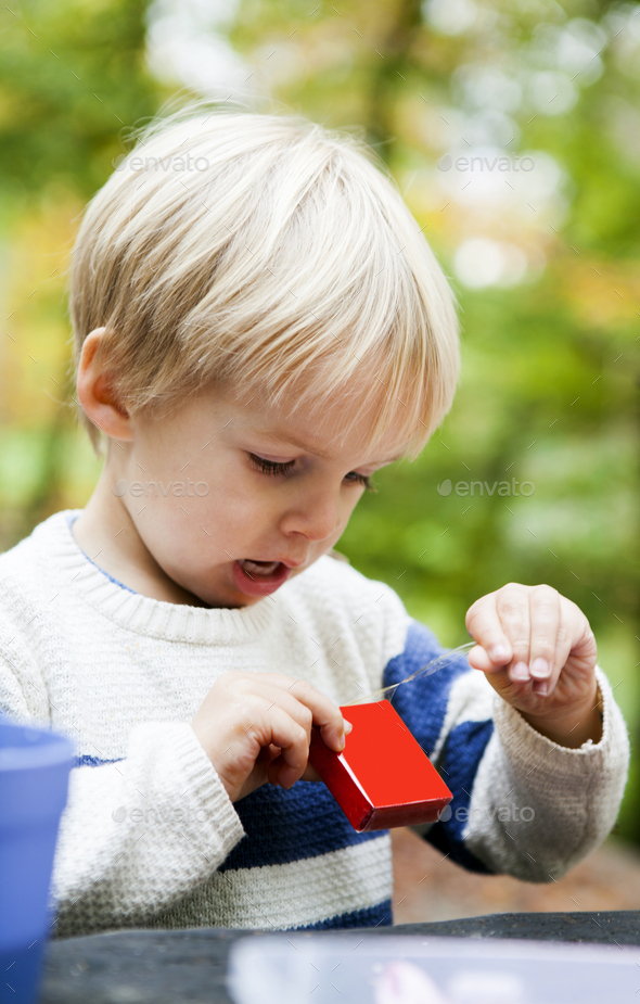 Cute boy opening package in forest Stock Photo by astrakanimages ...