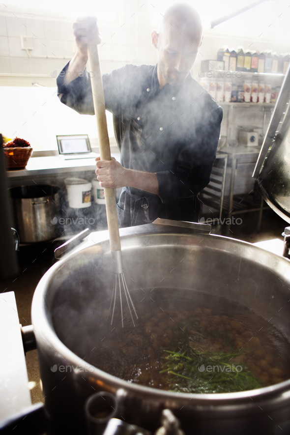 Male chef stirring food while preparing in restaurant kitchen Stock ...