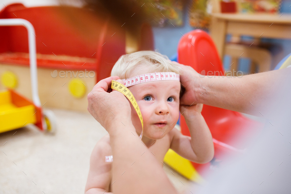 Baby (6-11 months) being measured by doctor Stock Photo by astrakanimages