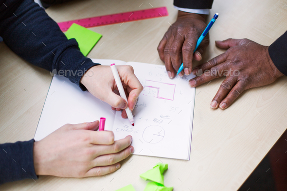 Student and teacher writing together Stock Photo by astrakanimages