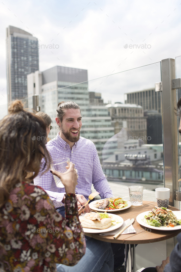 Friends enjoying meal at rooftop restaurant in city - Stock Image ...
