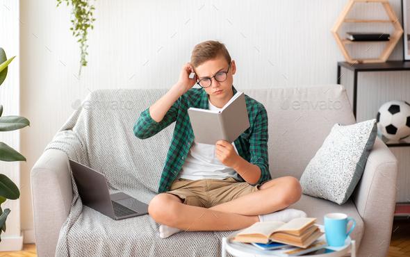 Confused nerd boy reading book, home education concept Stock Photo by ...