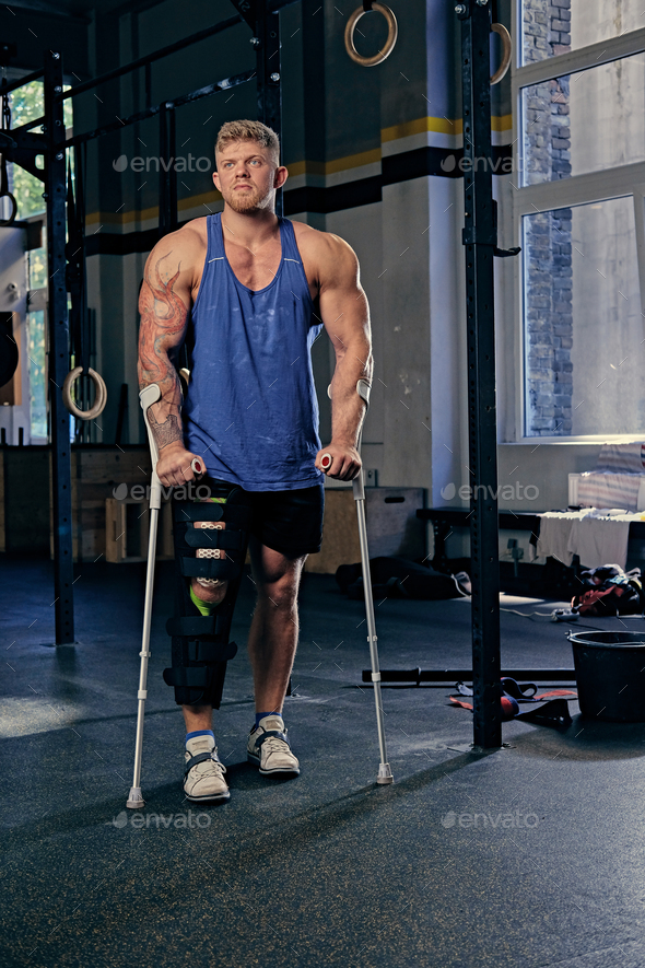 Bodybuilder on crutches in a gym club. Stock Photo by fxquadro | PhotoDune
