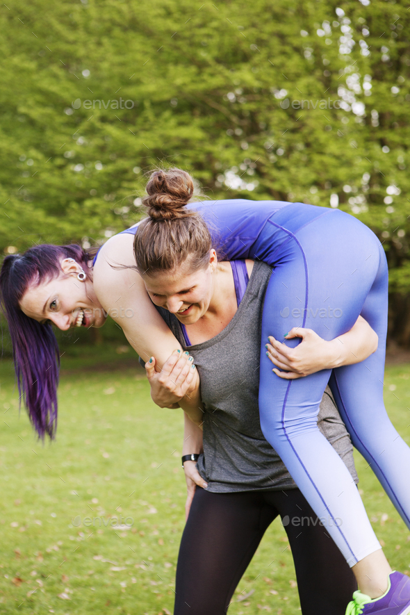 Woman carrying female friend while exercising at field Stock Photo by ...