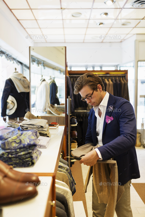 Salesman arranging t-shirt in rack at clothing store Stock Photo by ...