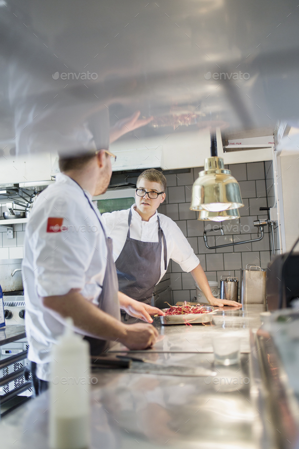 Chefs communicating in commercial kitchen Stock Photo by astrakanimages