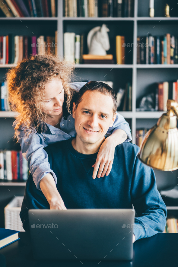 Couple working at home. Girl embracing her boyfriend. Happy couple ...