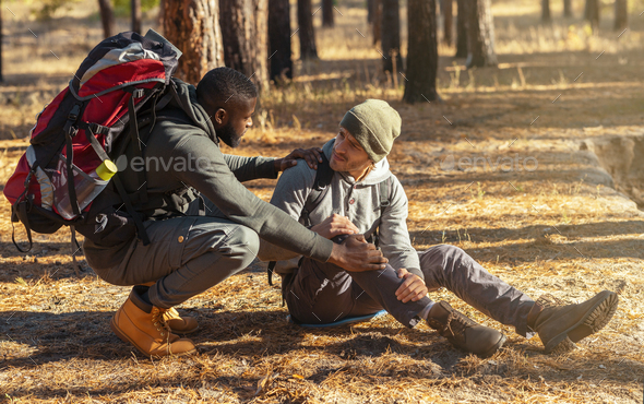 Black guy helping his injured friend, hiking together Stock Photo by ...