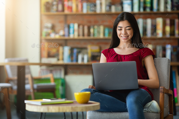 Smiling korean girl using laptop for online work or studies at cafe ...