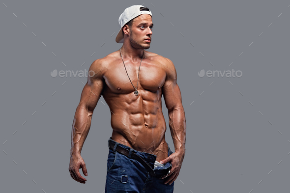 Muscular male in jeans and a white baseball cap. Stock Photo by fxquadro