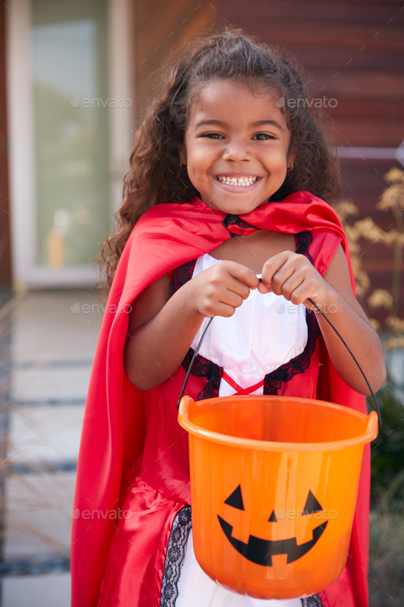 Portrait Of Girl Wearing Fancy Dress Outside House Collecting Candy For ...