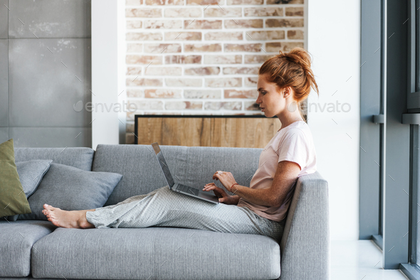 Image of focused woman working with laptop while sitting on couch Stock ...