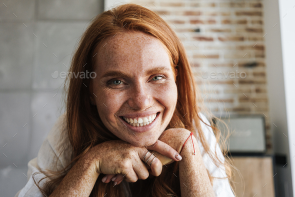 Image of happy ginger woman with freckles smiling and looking at camera ...