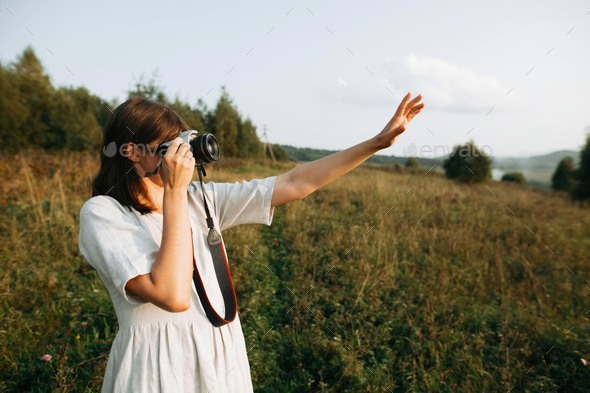Stylish boho girl taking photo on film analog photo camera of grass and ...