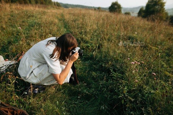 Stylish boho girl taking photo on film analog photo camera of grass and ...
