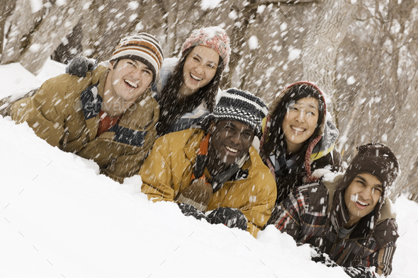 Five young people lying on the snow laughing. Snow falling. Stock Photo ...