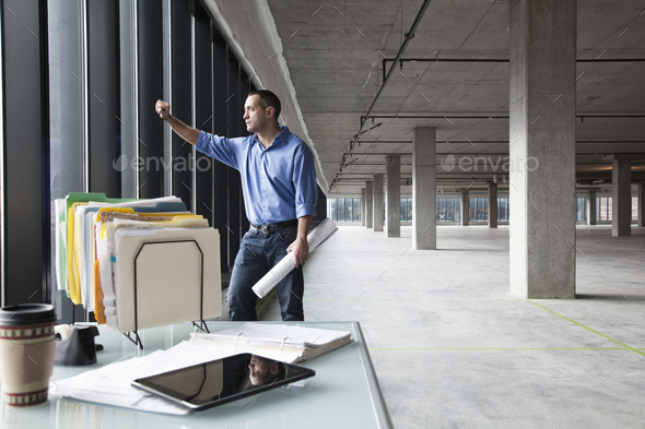 A Caucasian man at his temporary desk, in a new raw business space ...