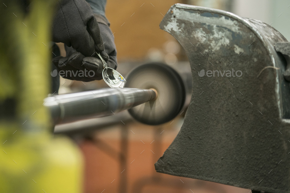 Silversmith polishing silver spoon using a small rotating disc on a ...