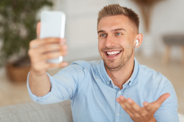 Happy guy using mobile phone for video call Stock Photo by Prostock-studio