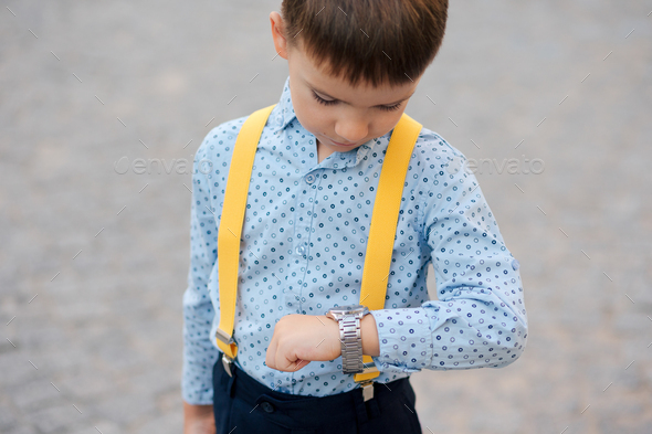 Boy verifying time on his silver watch on his hand Stock Photo by diignat