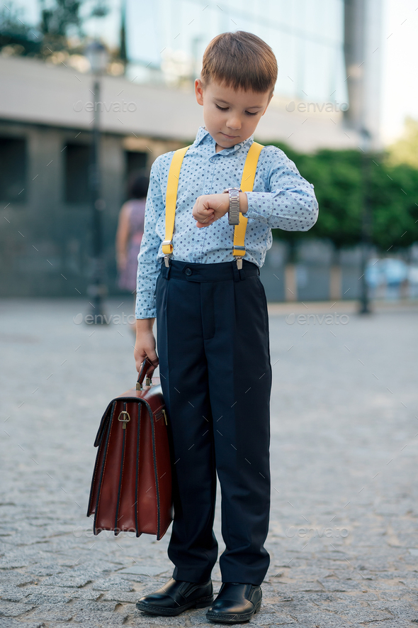 Boy verifying time on his silver watch on his hand Stock Photo by diignat