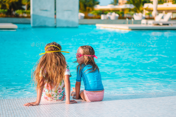 Adorable little girls playing in outdoor swimming pool on vacation ...