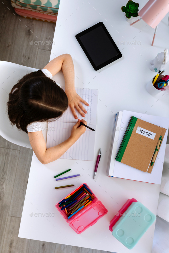 Girl doing homework sitting at a desk Stock Photo by davidpereiras