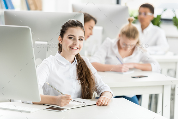 portrait of smiling teenage girl in white shirt looking at camera ...